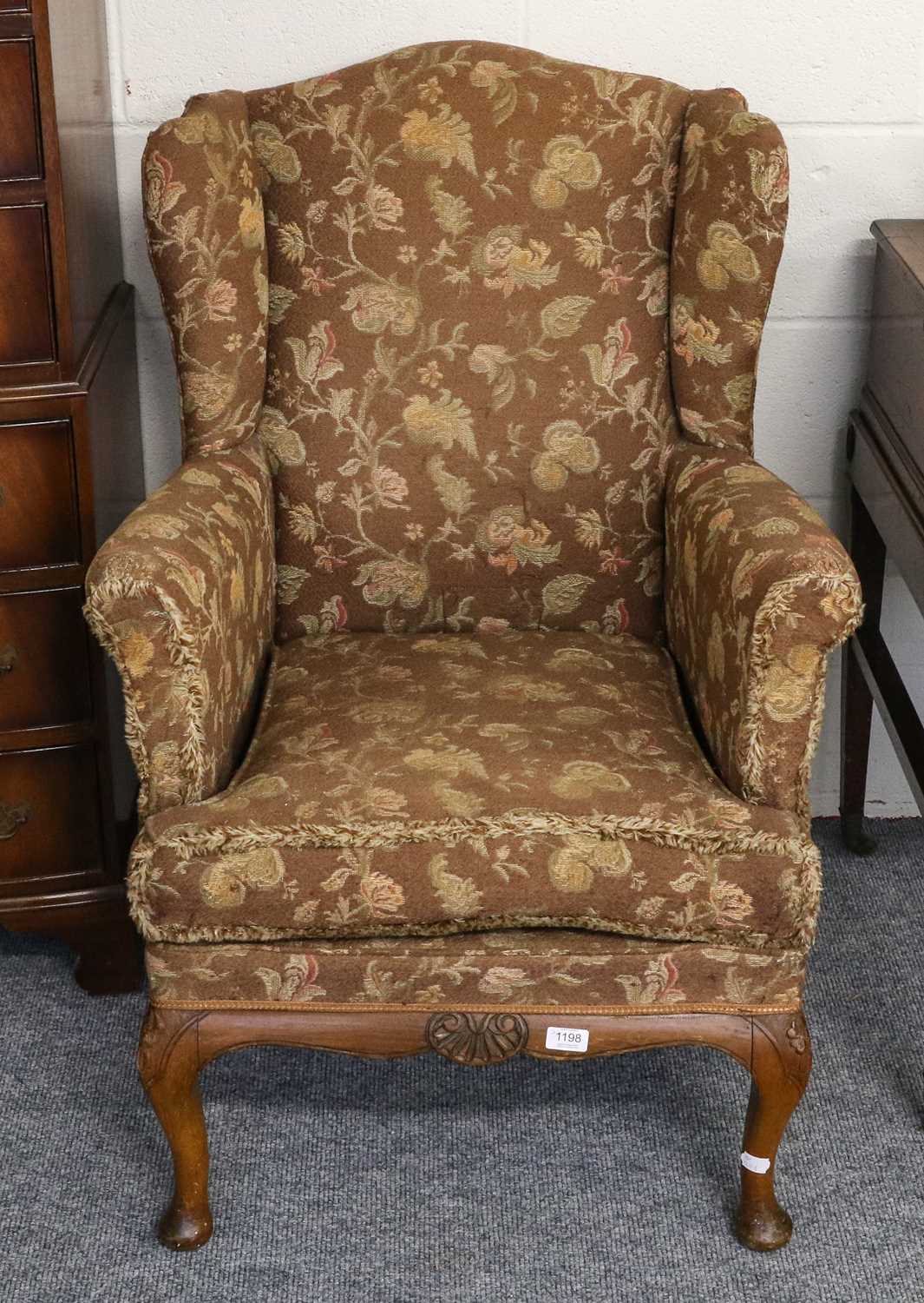 Lot 1198 - A 1920's wingback chair with carved frame,