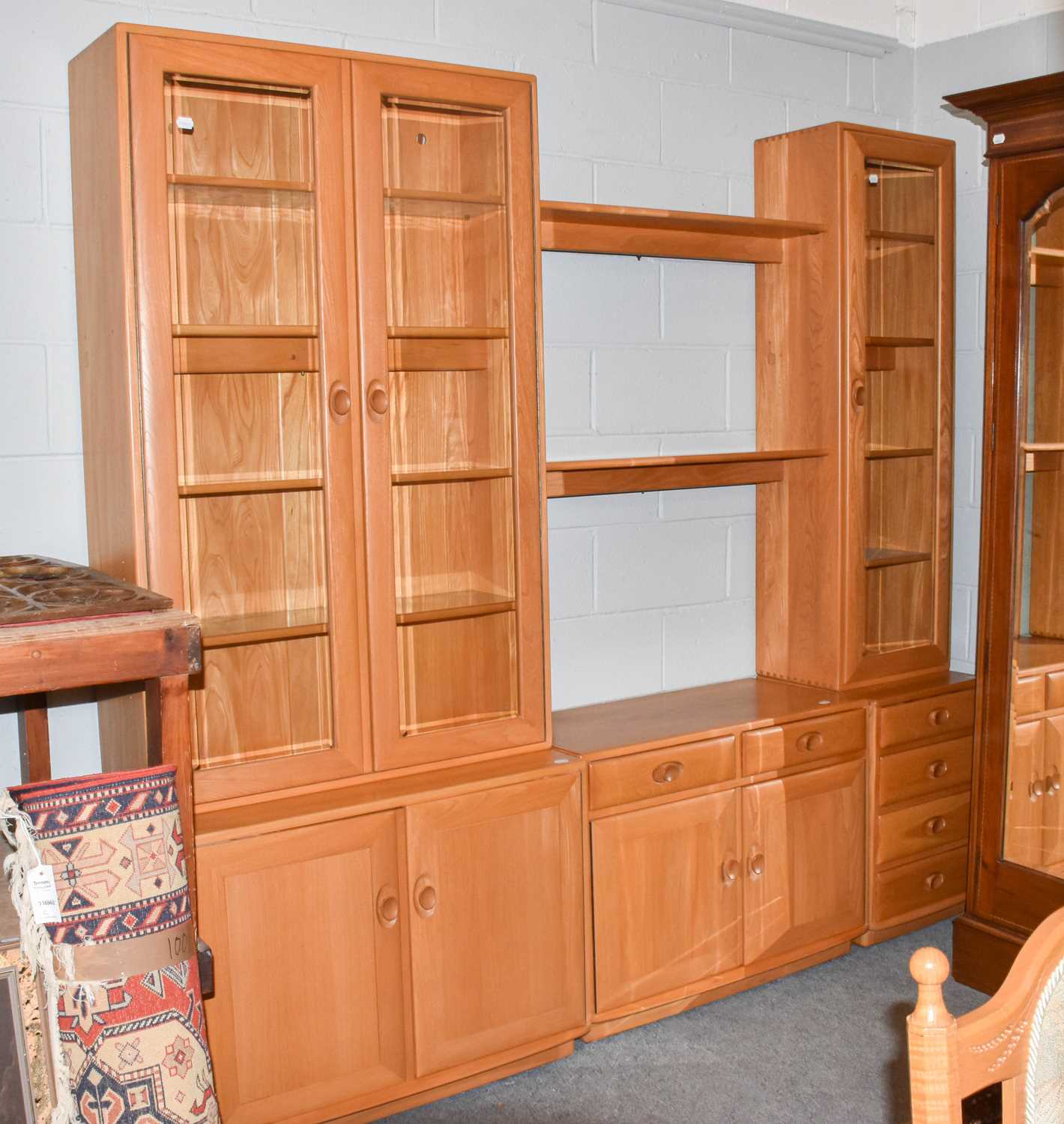 Lot 1174 - An ercol light elm wall unit, 231cm by 44cm